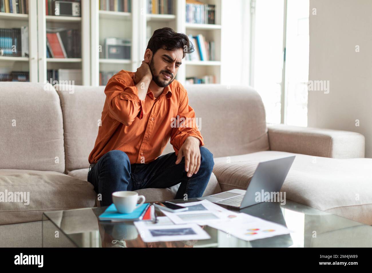 Tired stressed arab man having neck pain, working from home Stock Photo ...