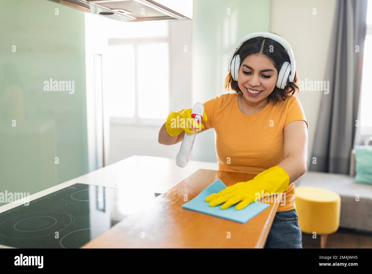 Happy Middle Eastern Female Cleaning Kitchen Counter With Detergent ...