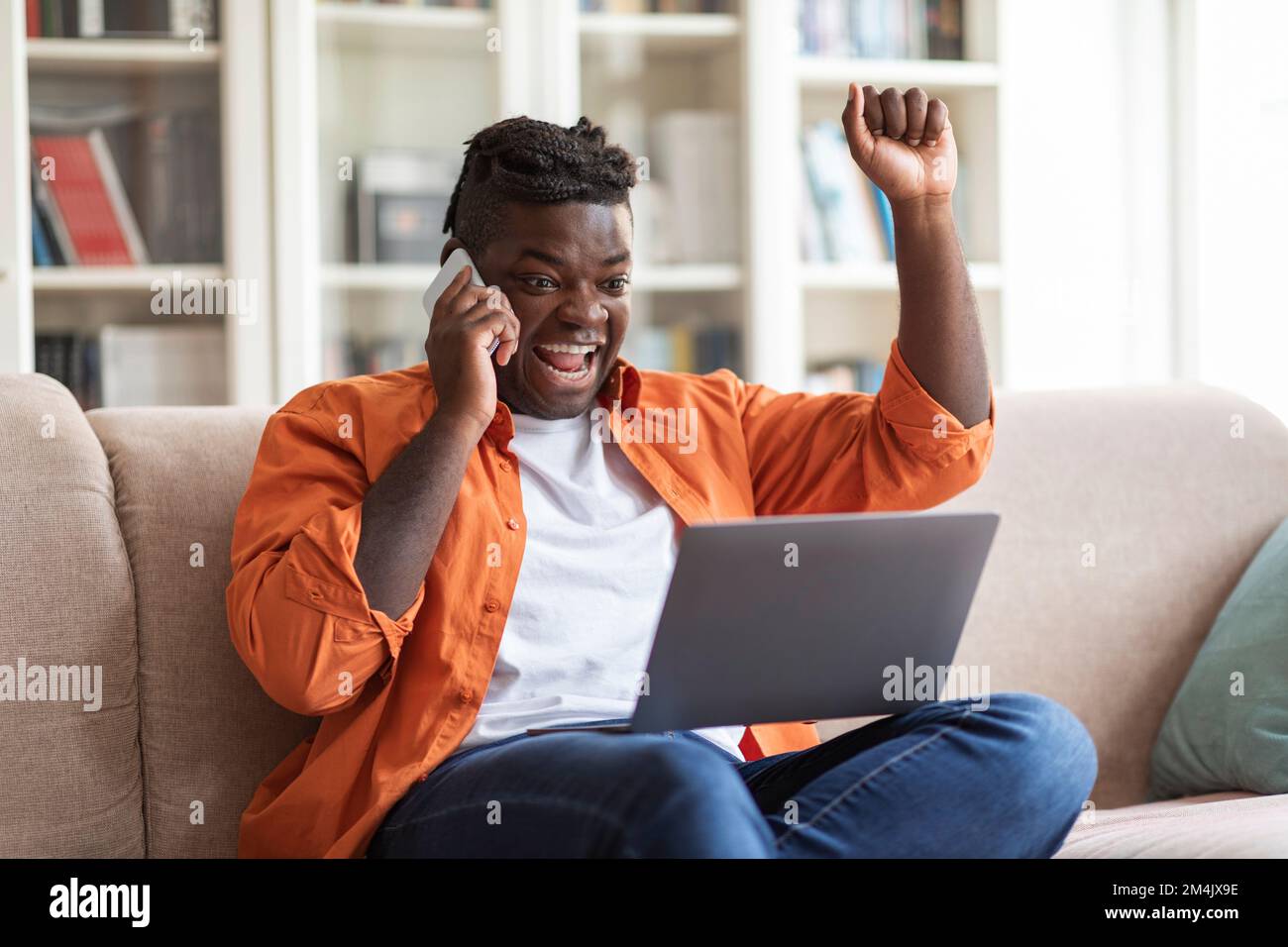 Emotional black guy entrepreneur celebrating success, having phone call ...