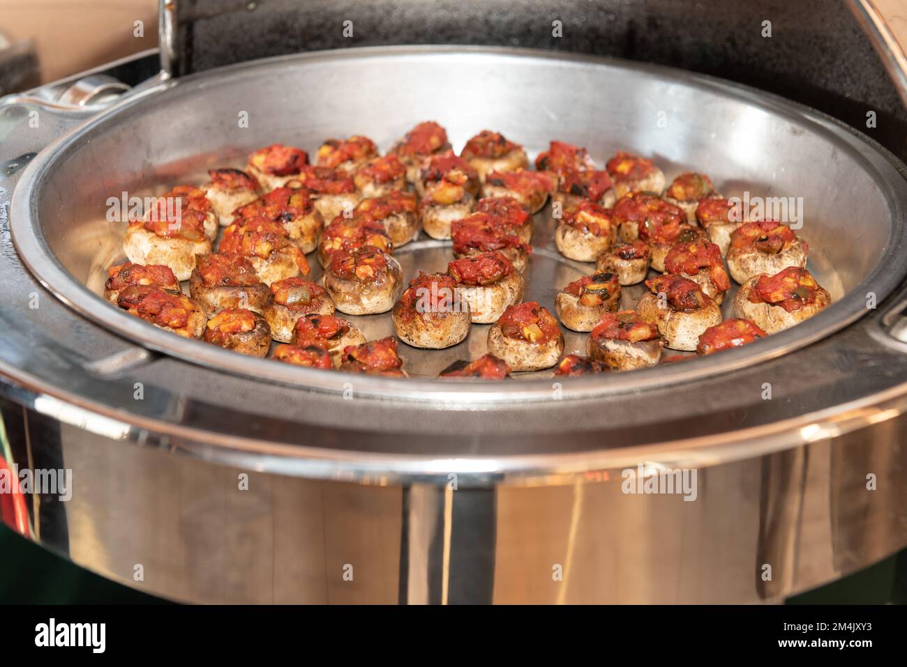 Buffet table has a chaffing dish with stuffed mushrooms for the party ...