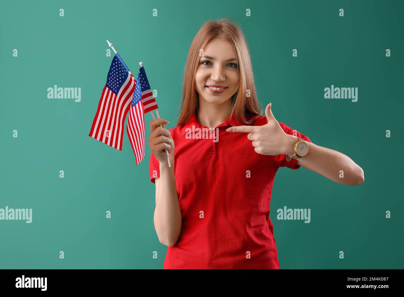 Young redhead woman pointing at USA flags on green background Stock ...