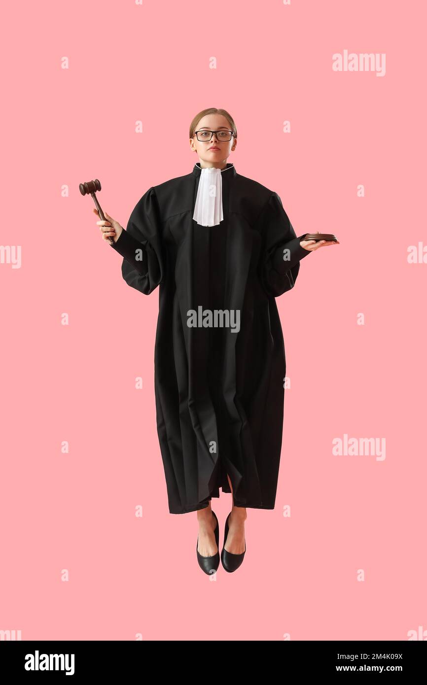 Young female judge with gavel jumping on pink background Stock Photo ...