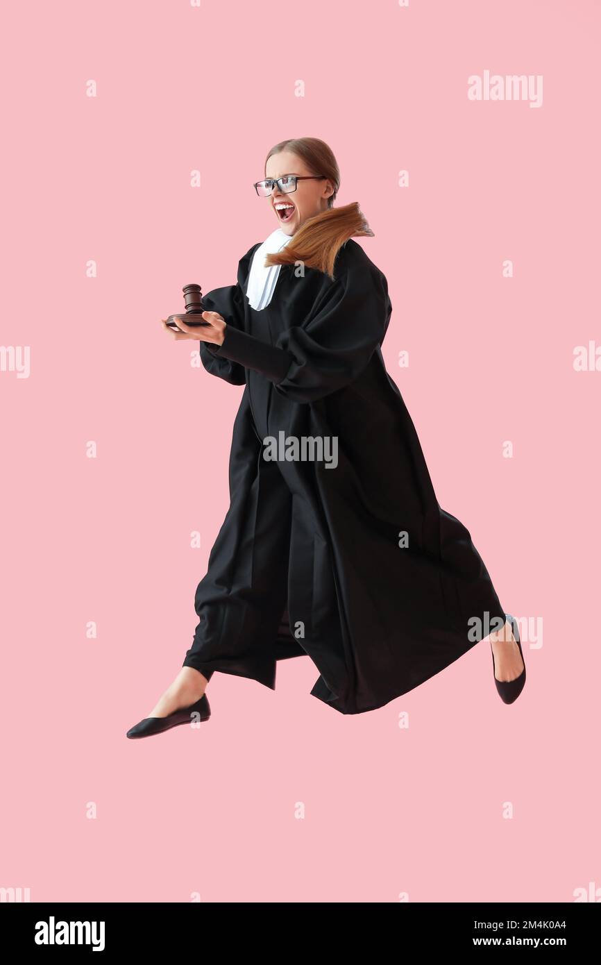 Angry female judge with gavel jumping on pink background Stock Photo ...