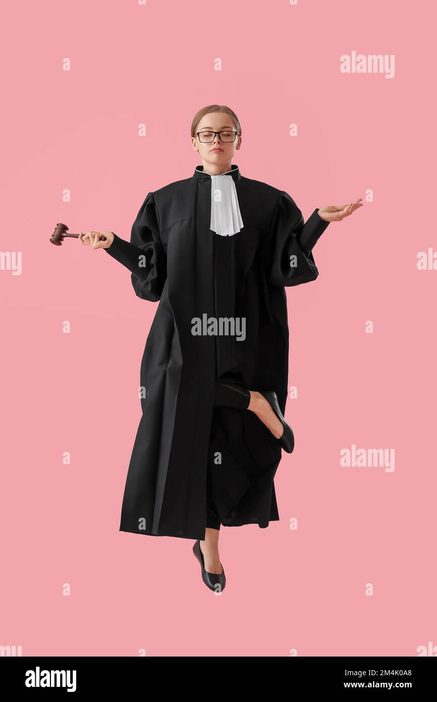 Young female judge with gavel jumping on pink background Stock Photo ...
