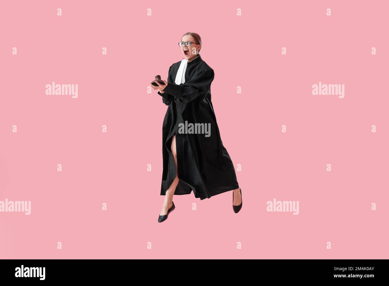 Angry female judge with gavel jumping on pink background Stock Photo ...