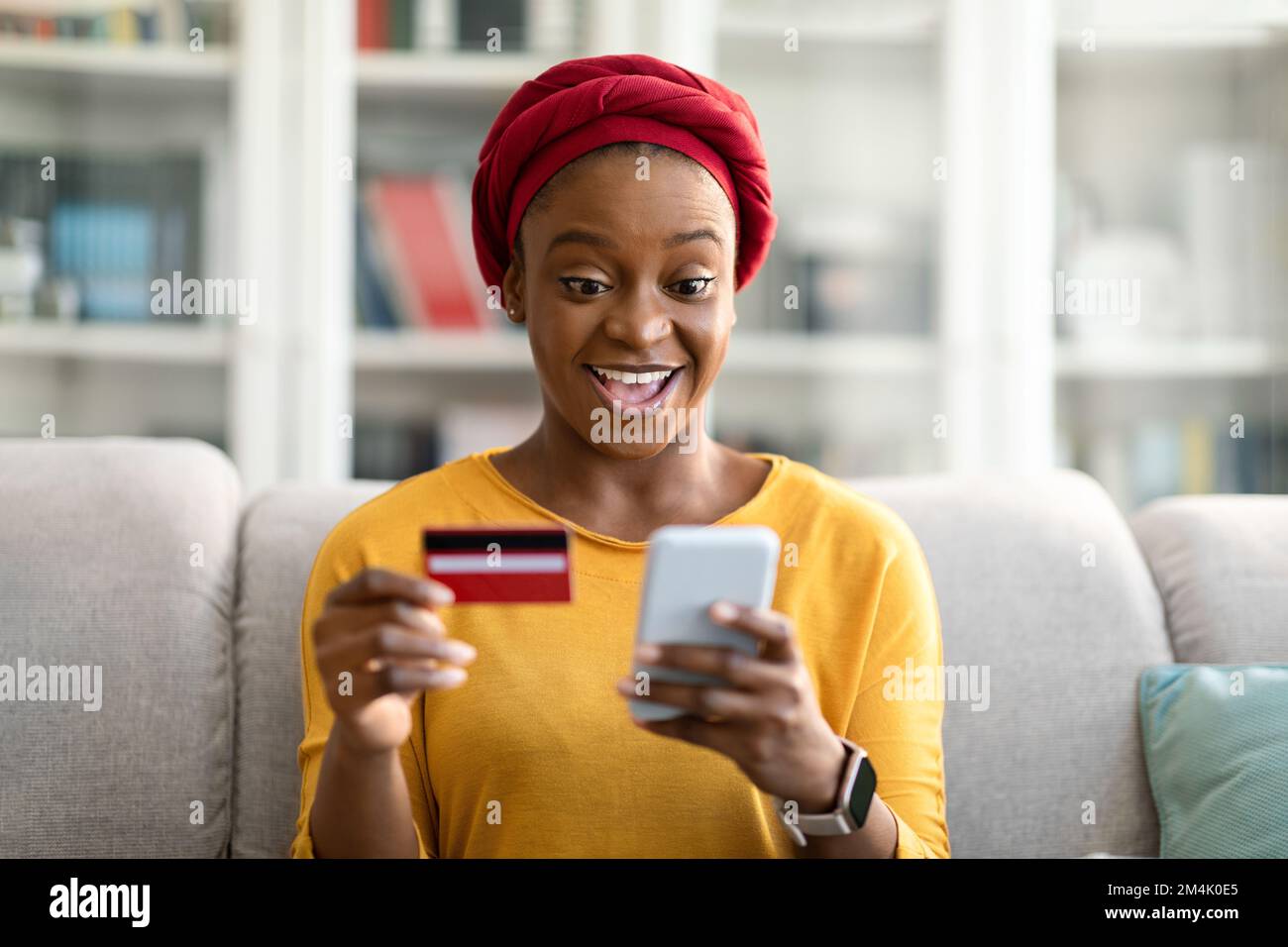 Excited african american woman using credit card and phone Stock Photo ...