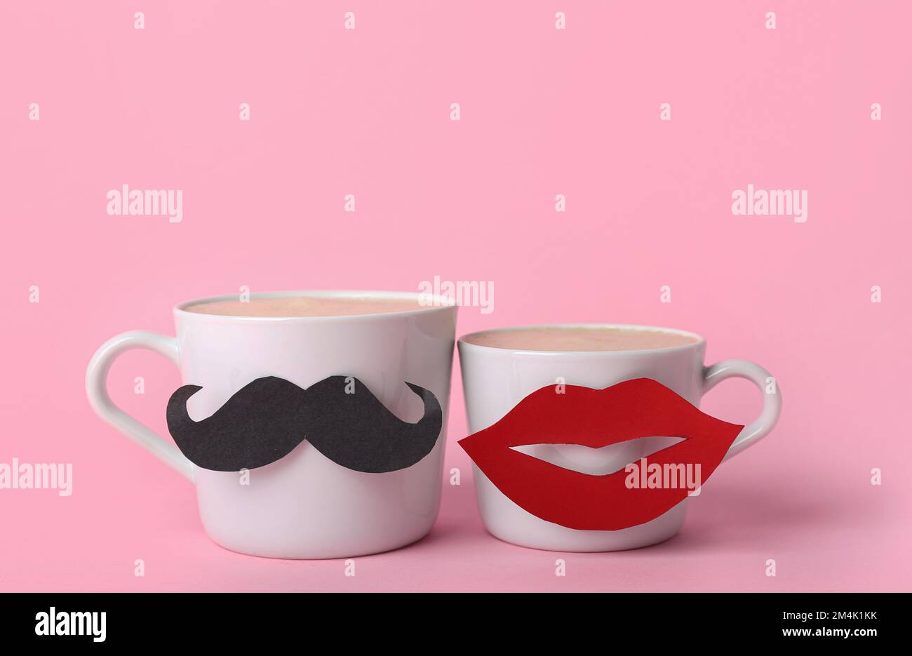 Cups of coffee with paper moustache and lips on pink background ...