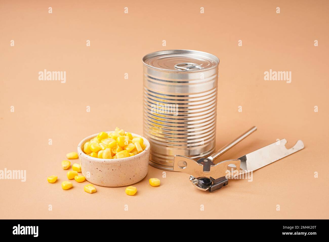 Tin can, bowl with corn kernels and opener on beige background Stock ...