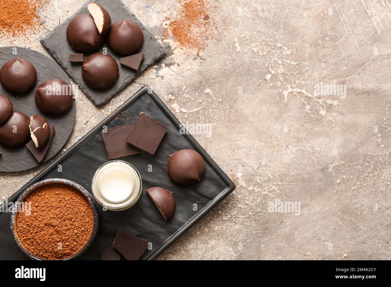 Boards with sweet chocolate bird's milk candies and pitcher of milk on ...