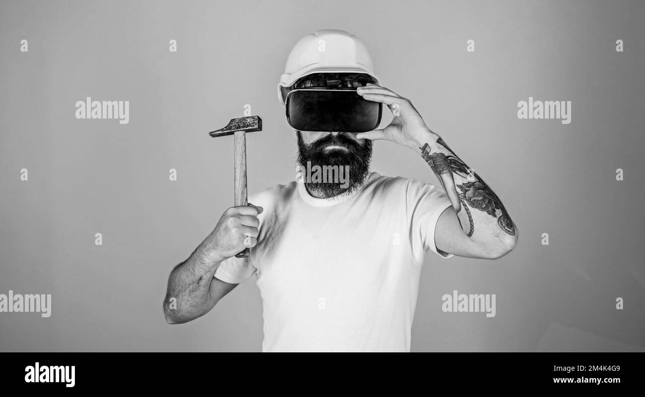 Hipster on serious face wear helmet, hold hammer in virtual reality ...
