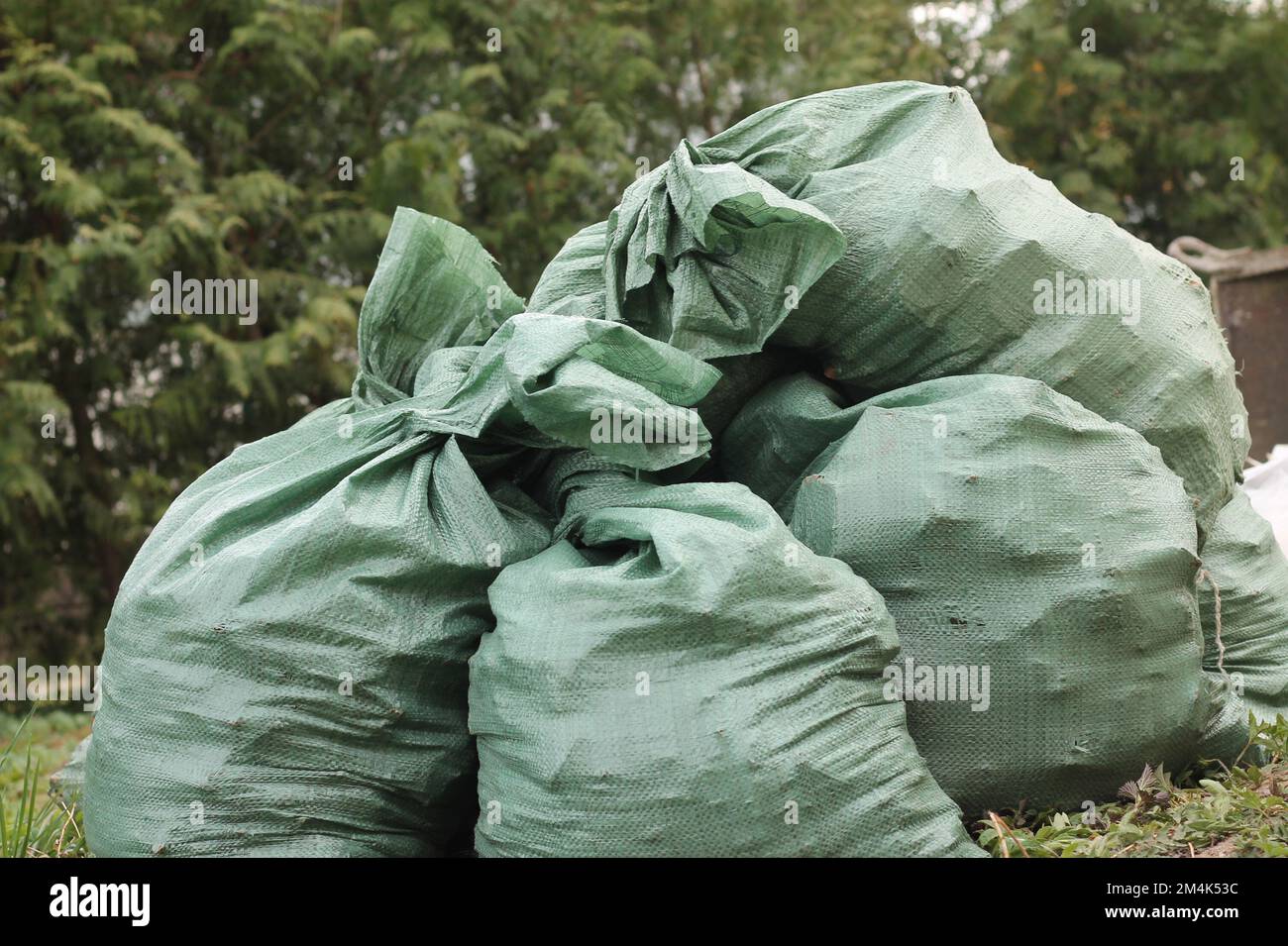 Pile of green plastic free ecological trash bags on dump outdoors ...