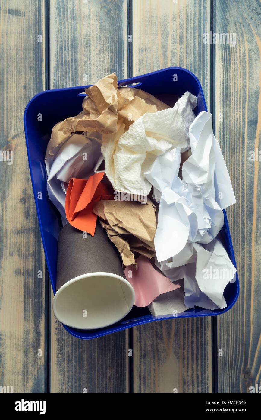 Vertical blue plastic container box full of waste, rubbish on wooden ...