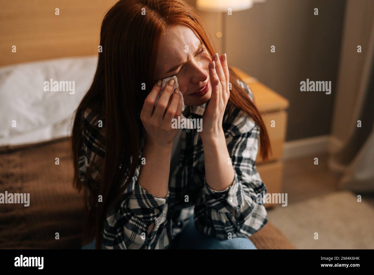 Close-up portrait of unhappy depressed redhead woman crying and wiping ...