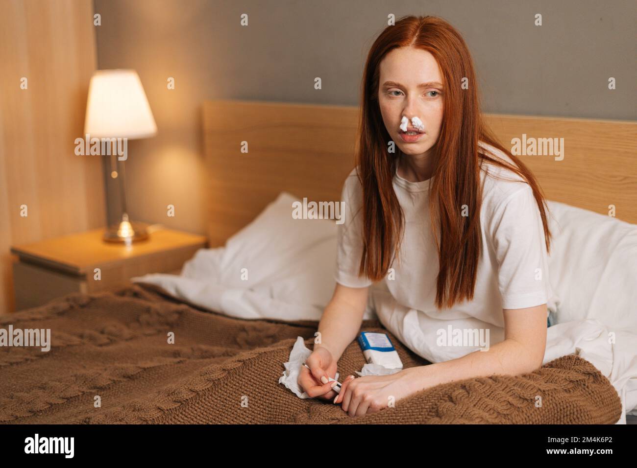 Sick woman with flu virus touching head temple after using thermometer ...