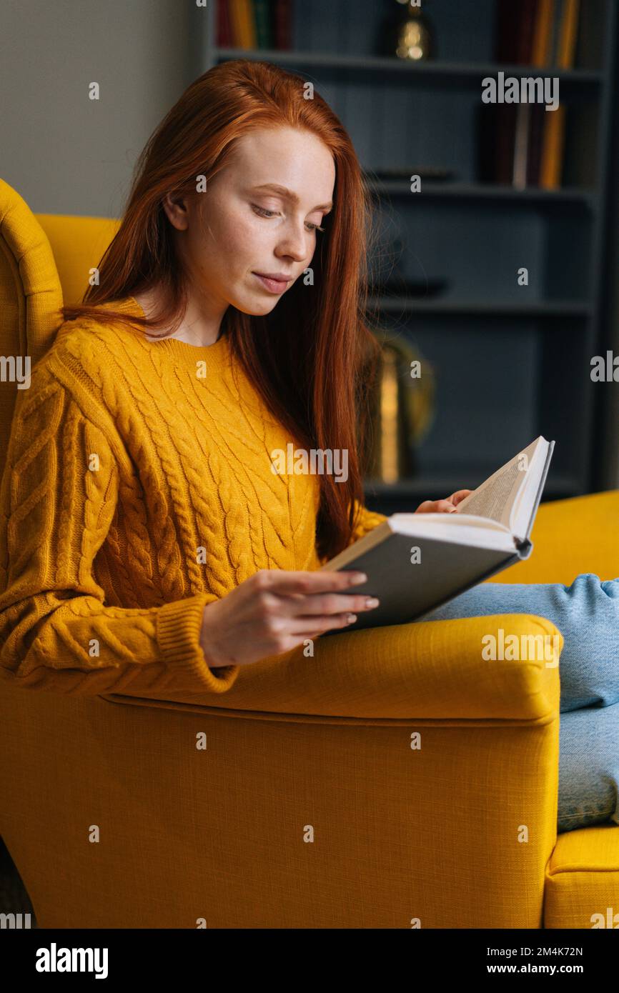 Vertical portrait of pretty young woman reading exciting story having ...
