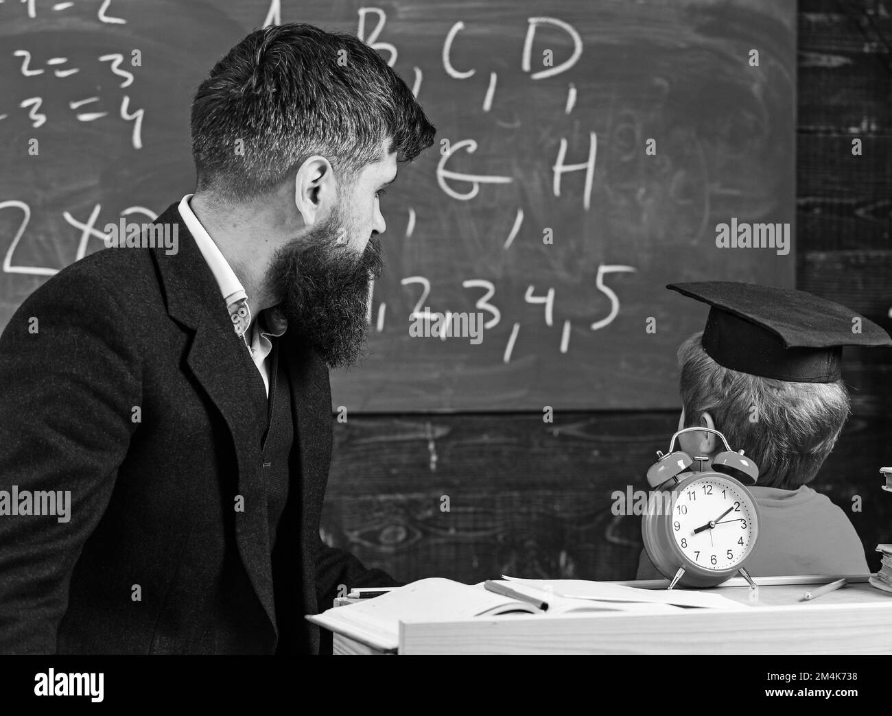 Young male teacher guides his child student to learning while son looks ...