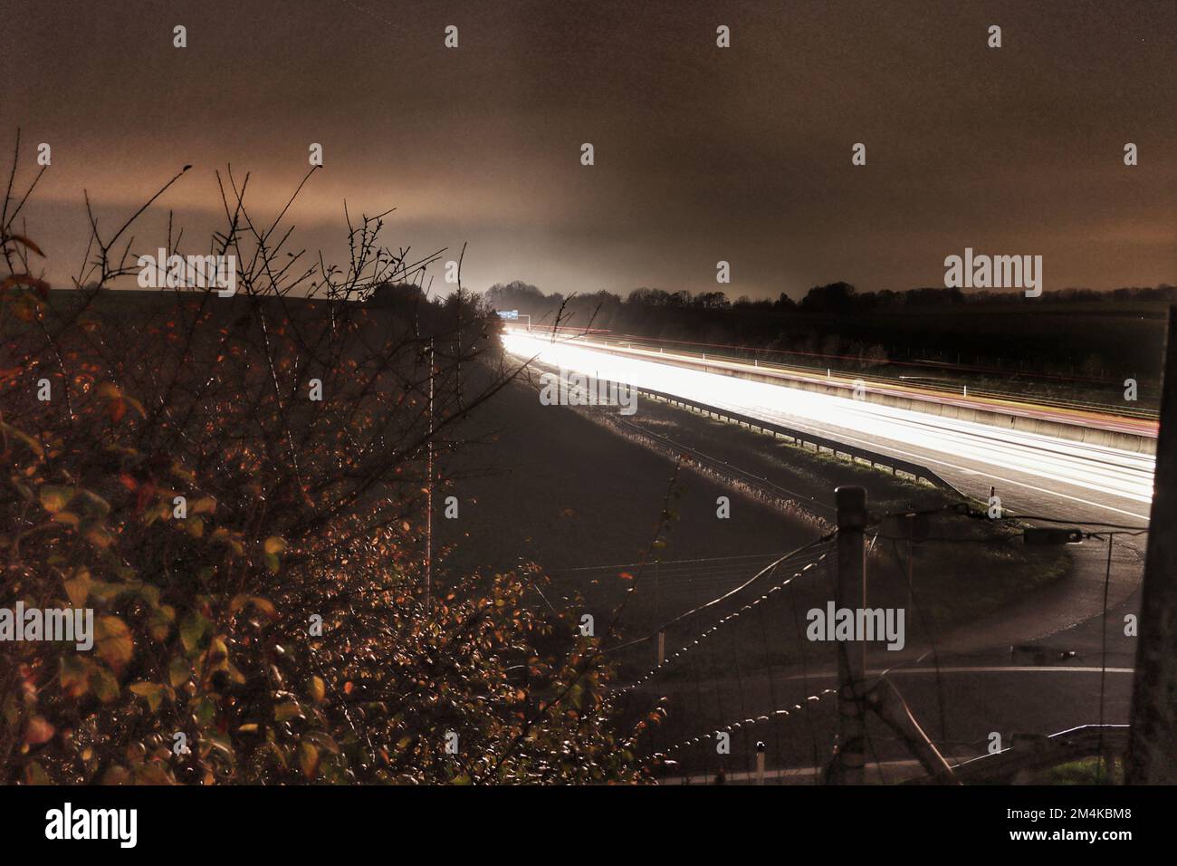 A long exposure shot of traffic lights on a highway surrounded by the ...