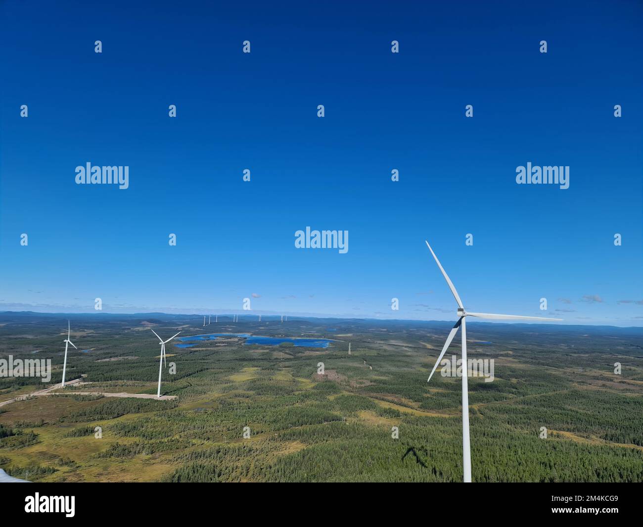 An aerial view of green valleys and hills with tall wind turbines under ...