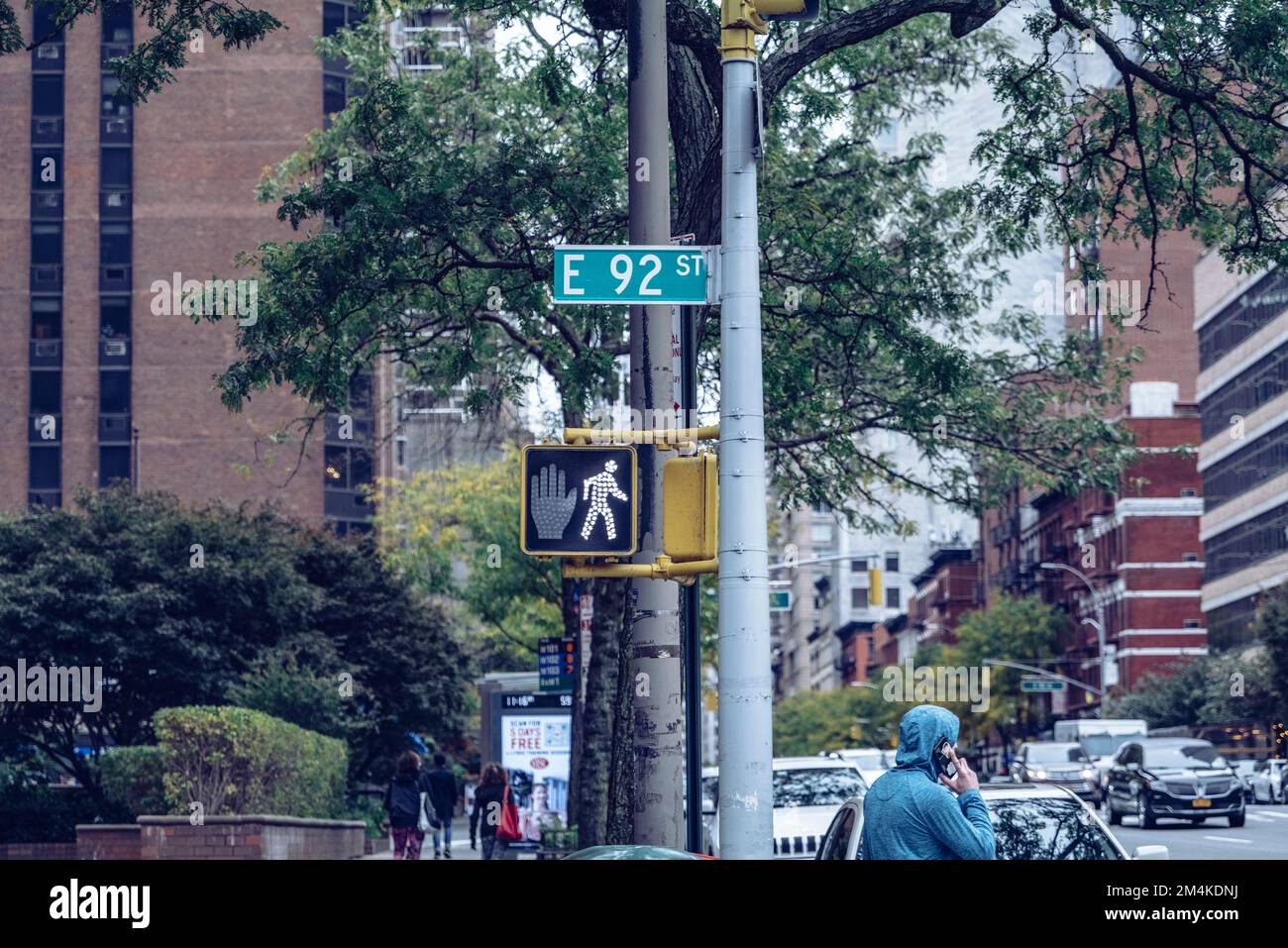 East 92 street sign in Manhattan, can walk signal, and a man holding ...