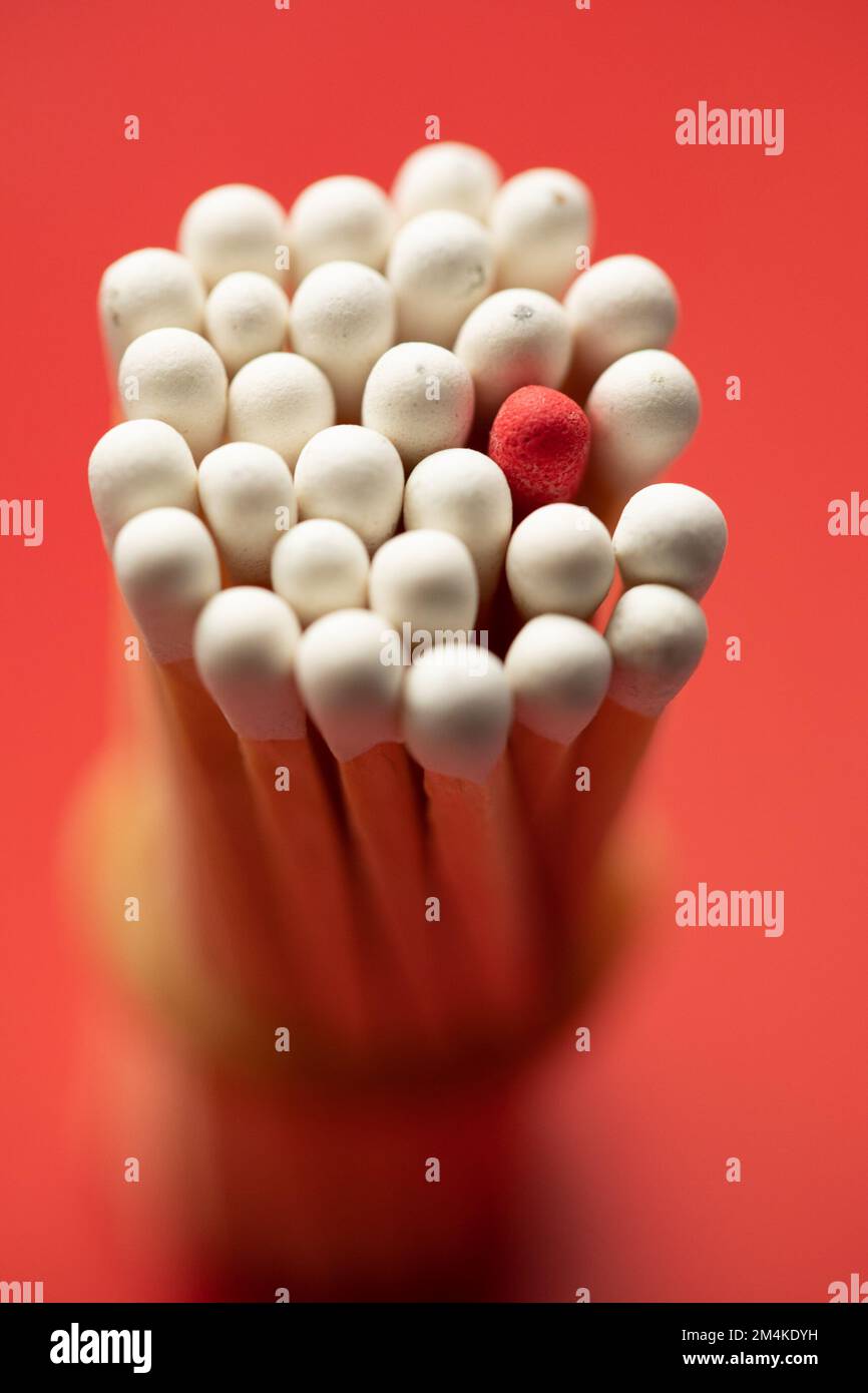 A vertical shot of white matches and a pink one in a container on a ...