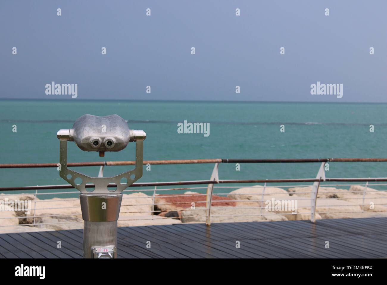 An outdoor telescope on a wooden dock protected with railings ...