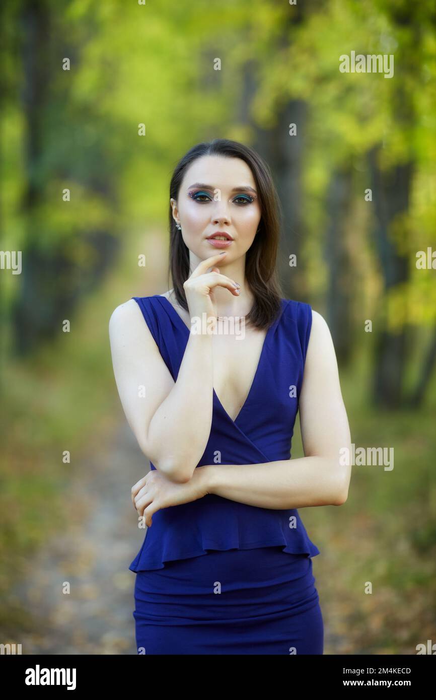 Female in blue dress walking along autumn linden tree alley. Path under ...