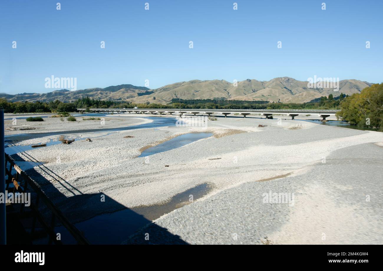 View from bridge across shingle river bed to bridge and hills in South ...