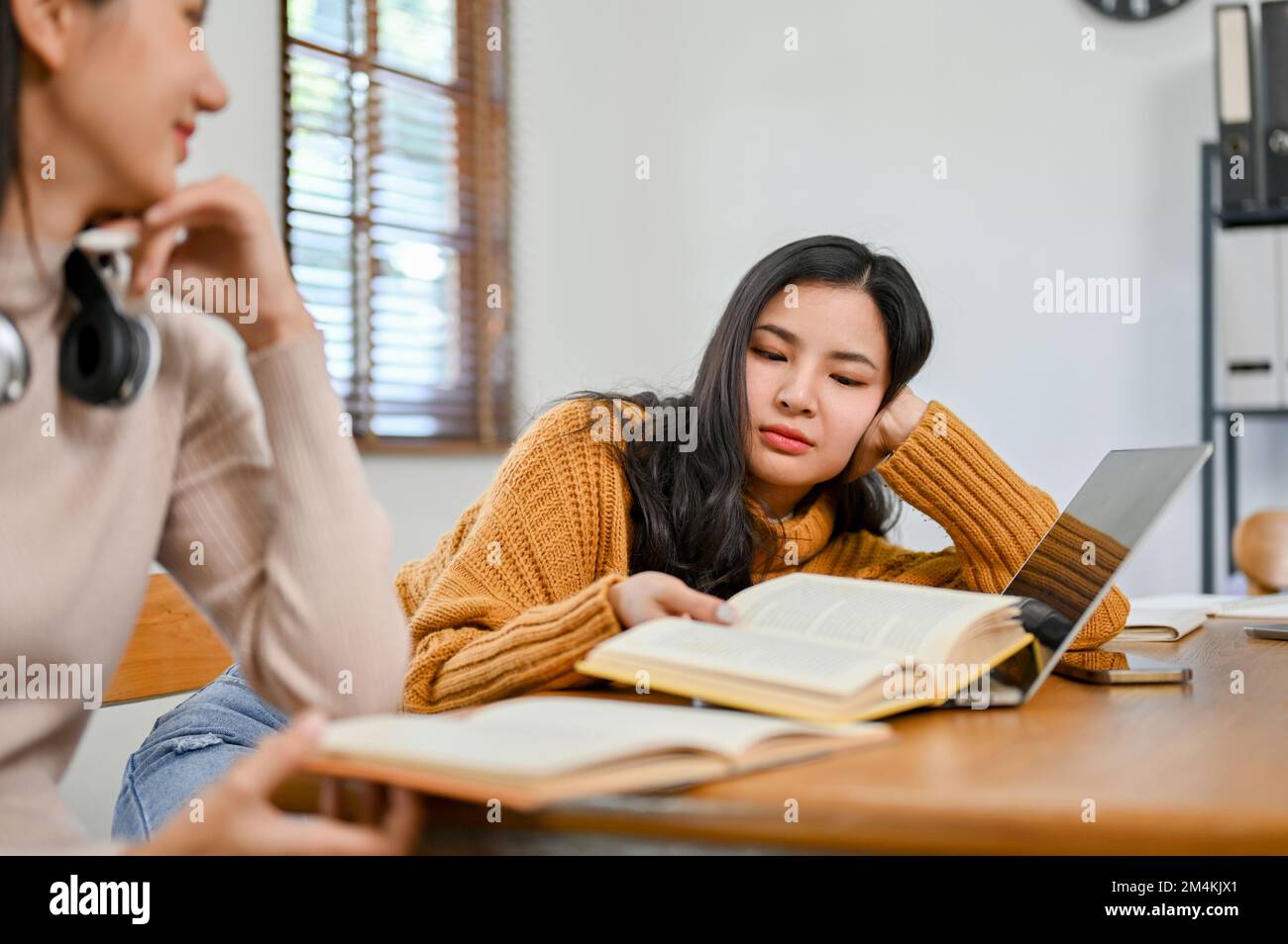 Bored, tired and sleepy young Asian female college student preparing ...