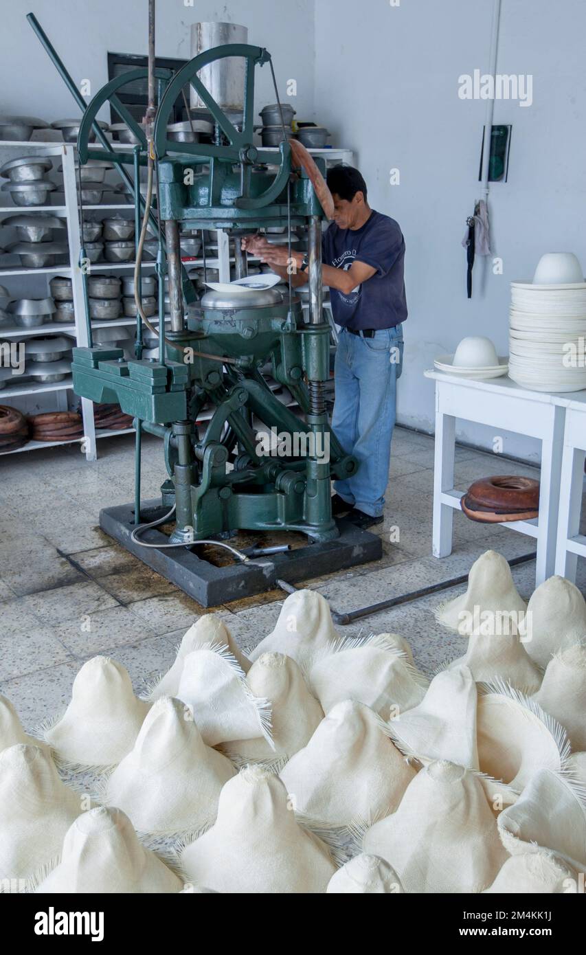 A worker pressing a toquilla straw hat, also known as a Panama hat into ...