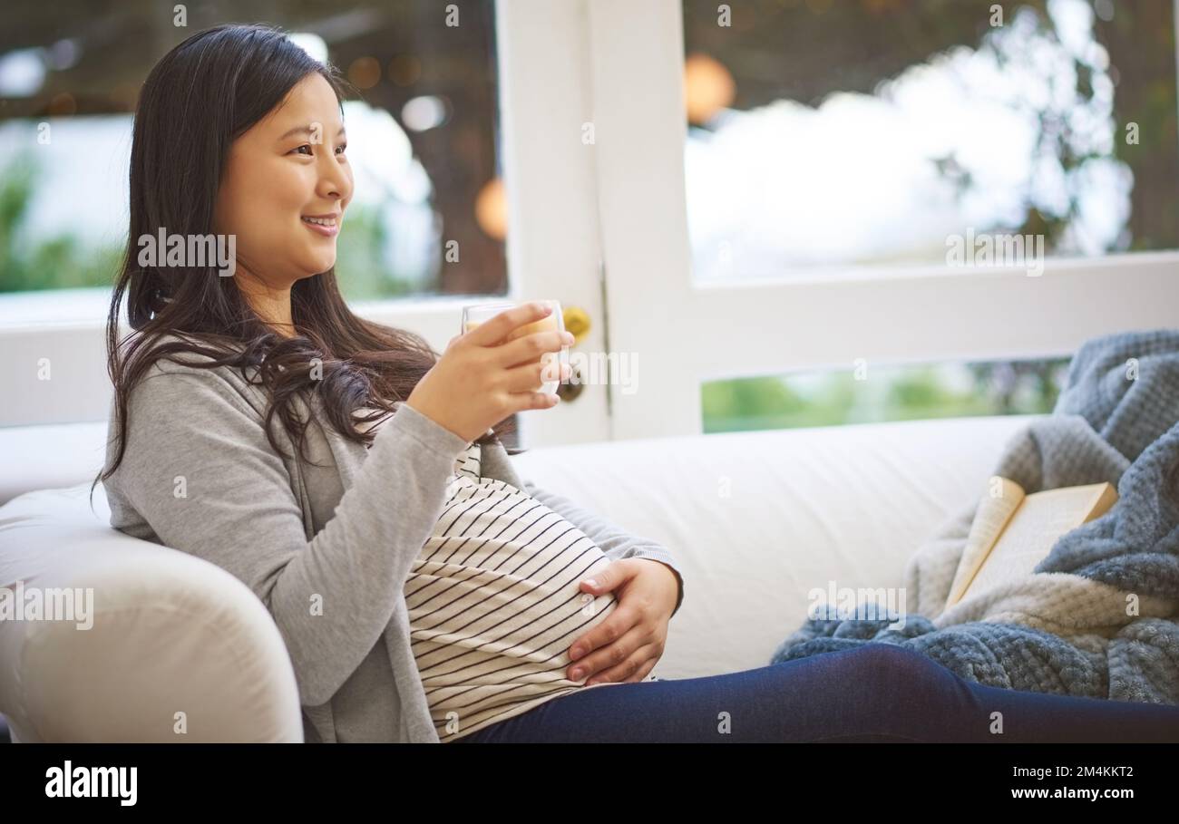 Indulge those cravings. an attractive young pregnant woman drinking an iced coffee while ...