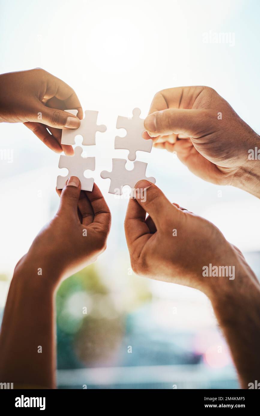 Together well find the answer. businesspeople completing a puzzle ...