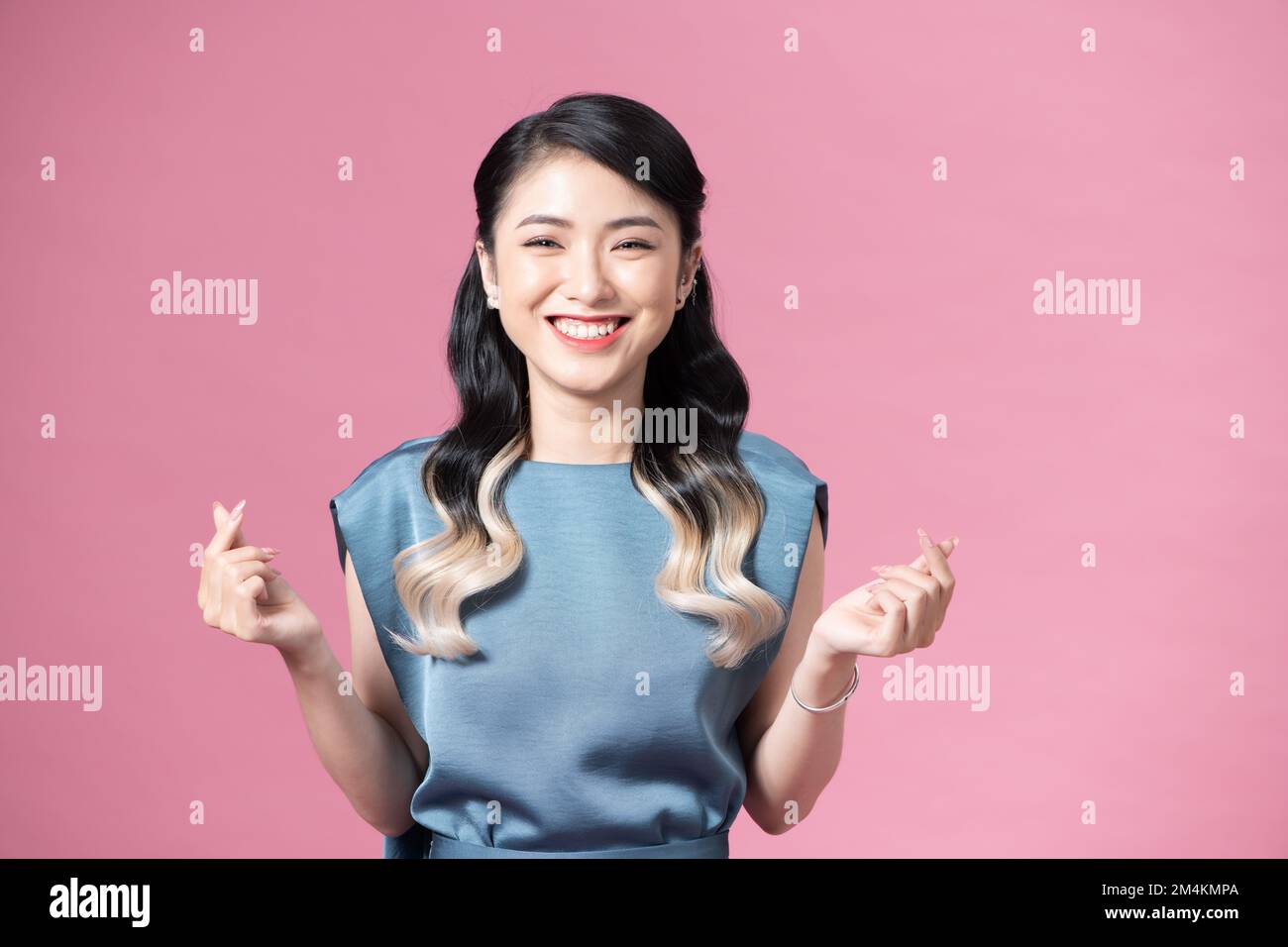 Young Asian woman showing mini heart sign isolated on pink background ...