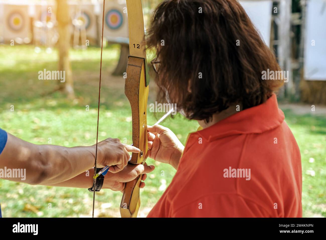 Female teacher teaches student to aim at goal. An archer teaching young ...