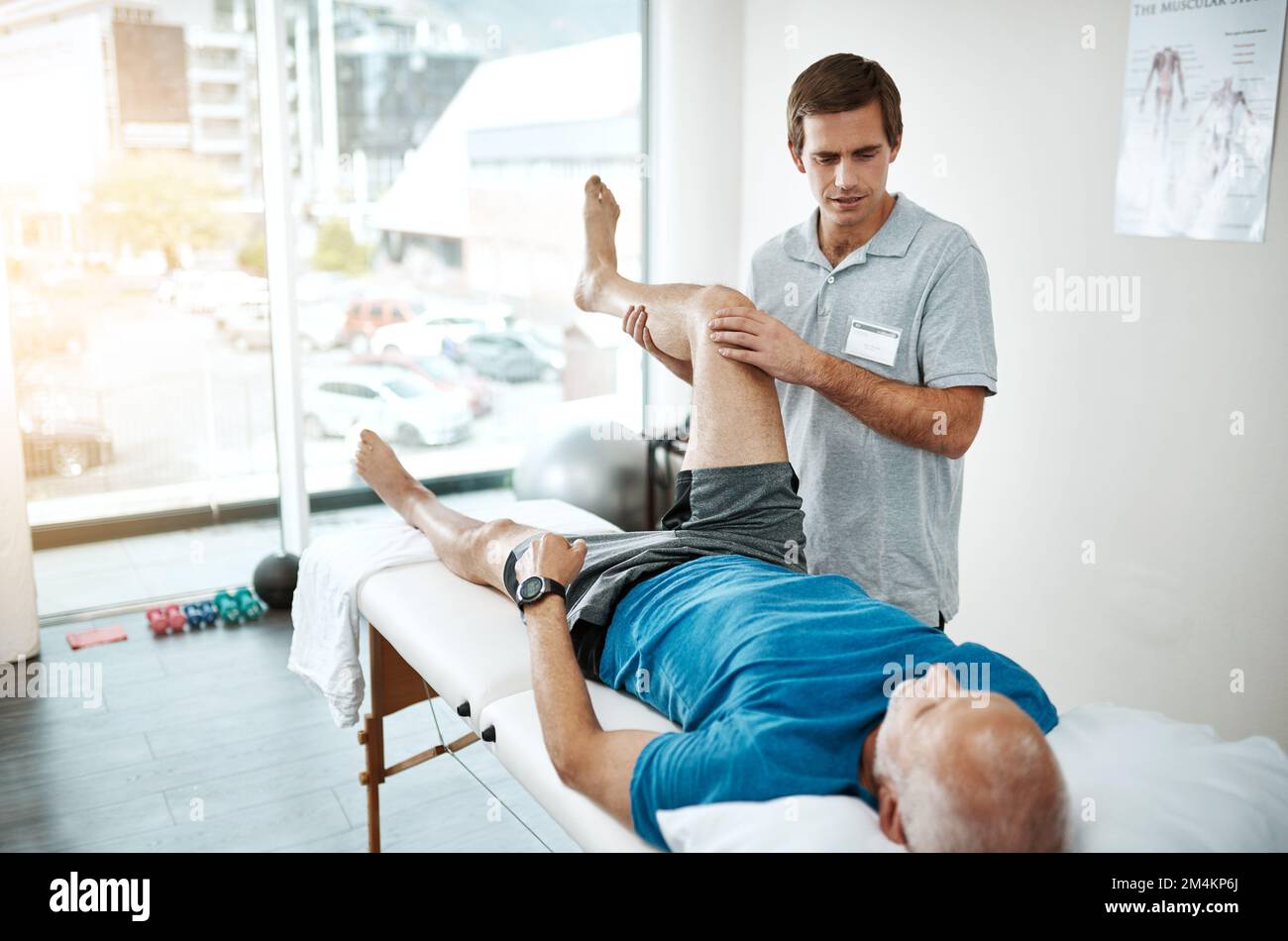 tell me where it hurts sir. a young male physiotherapist helping a ...