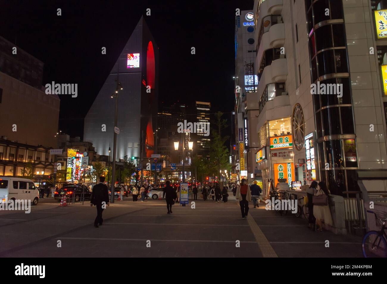 The streetlife at night in Japan with lots of people walking past the ...