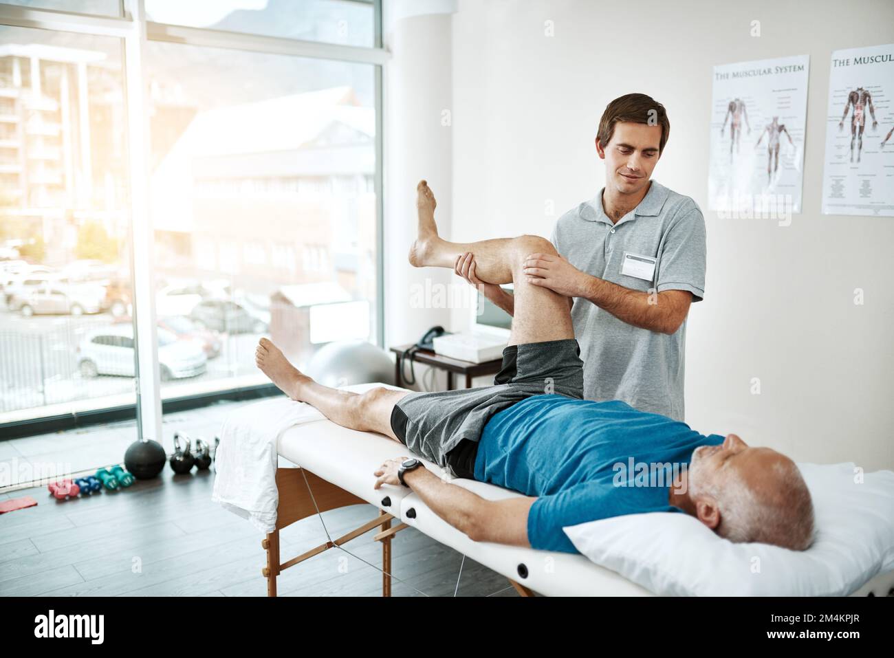 Lets lift this leg up shall we. a young male physiotherapist helping a ...