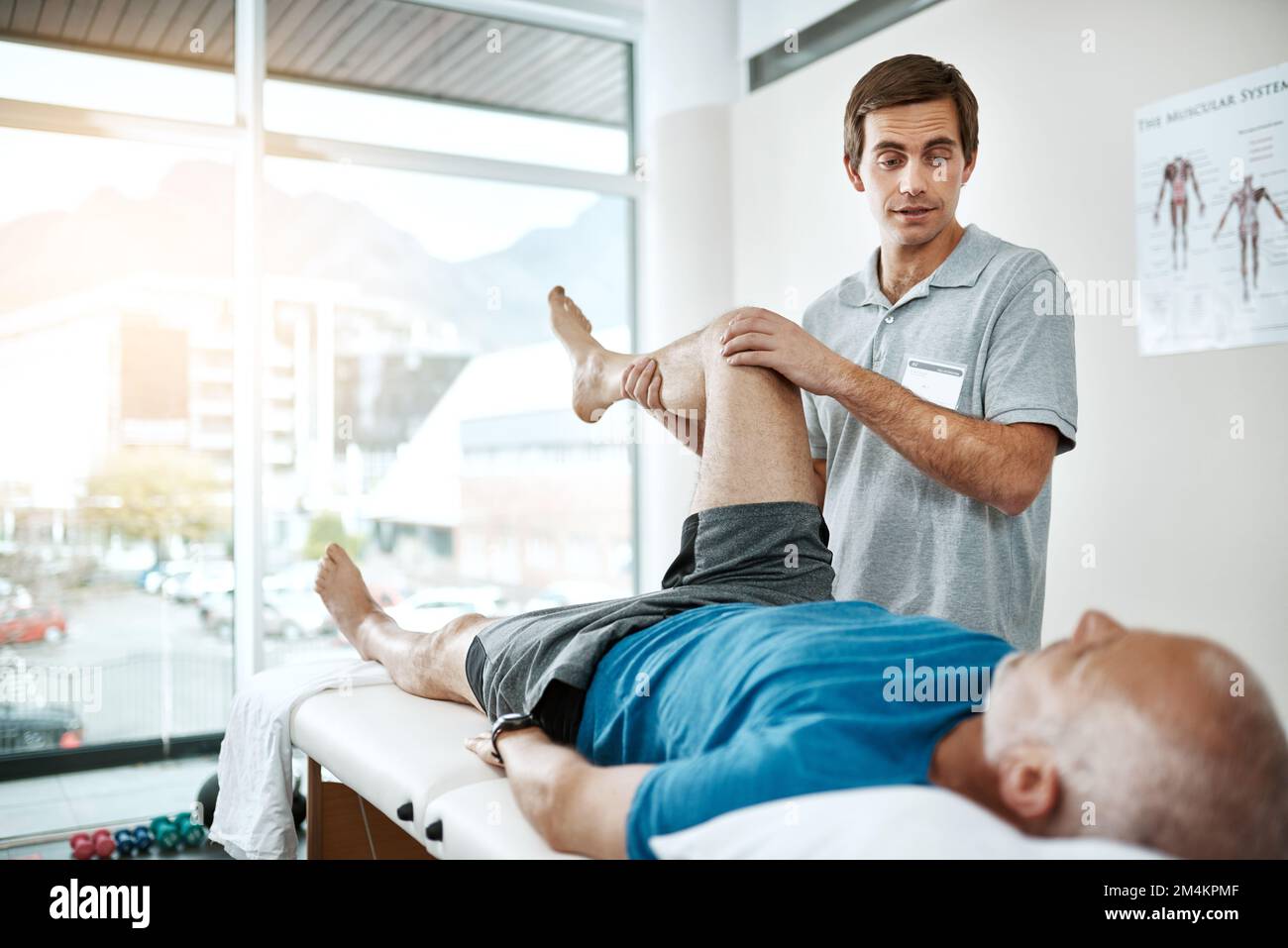 Try to relax. a young male physiotherapist helping a client with leg ...