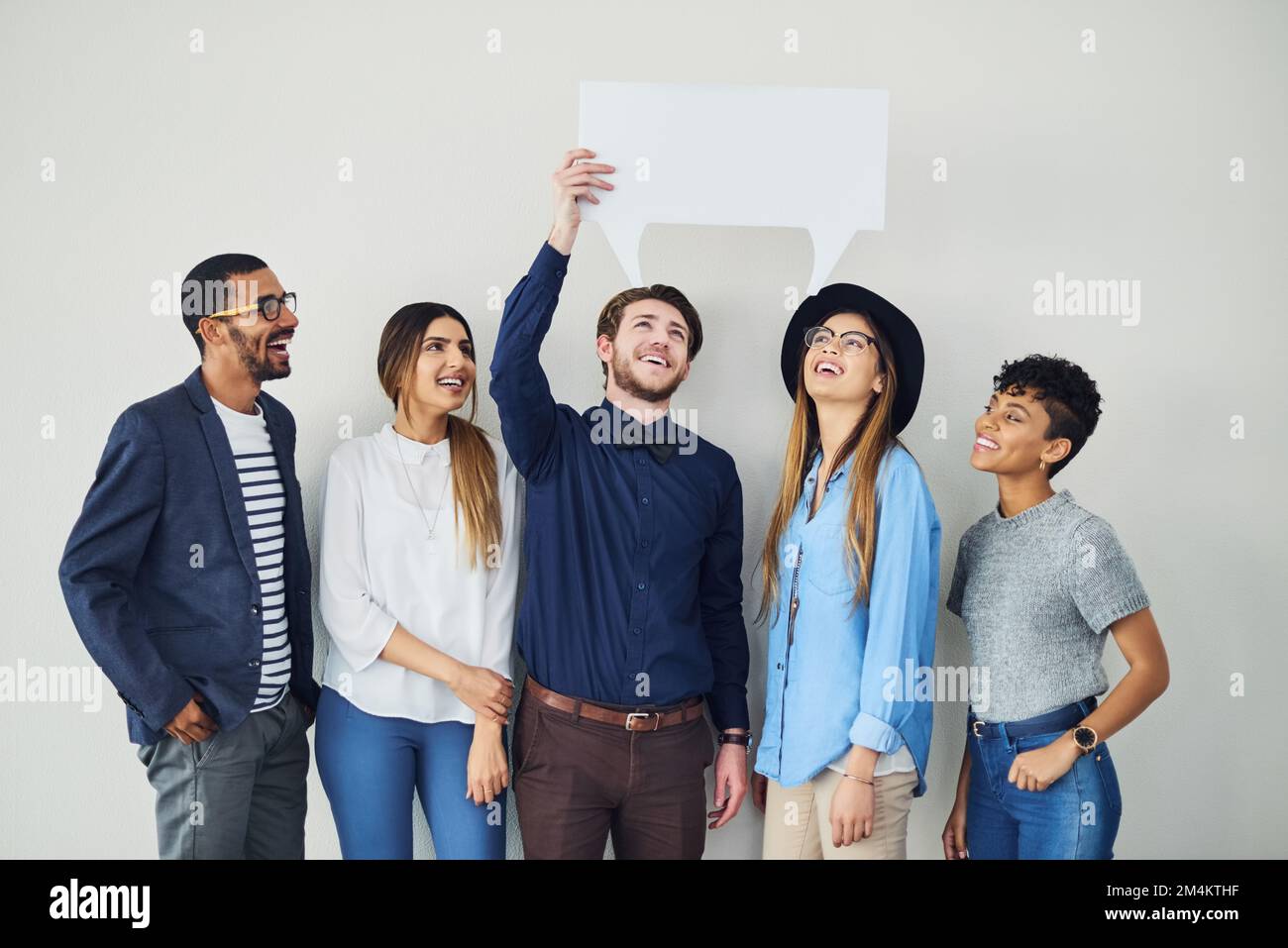 Lets say it together. a diverse group of creative employees holding up ...