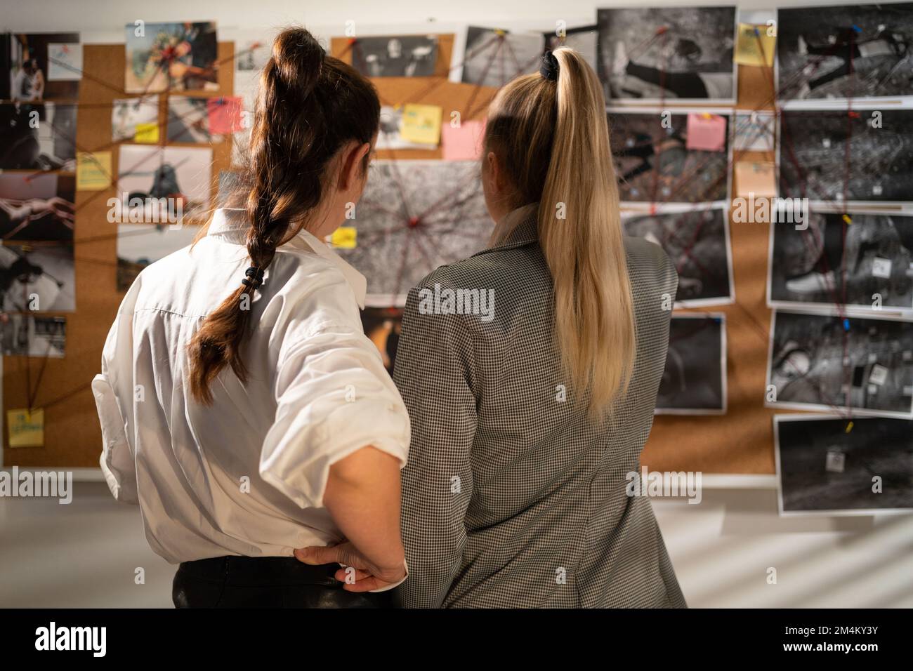 Smart detectives looking attentively at investigation board, evaluating ...