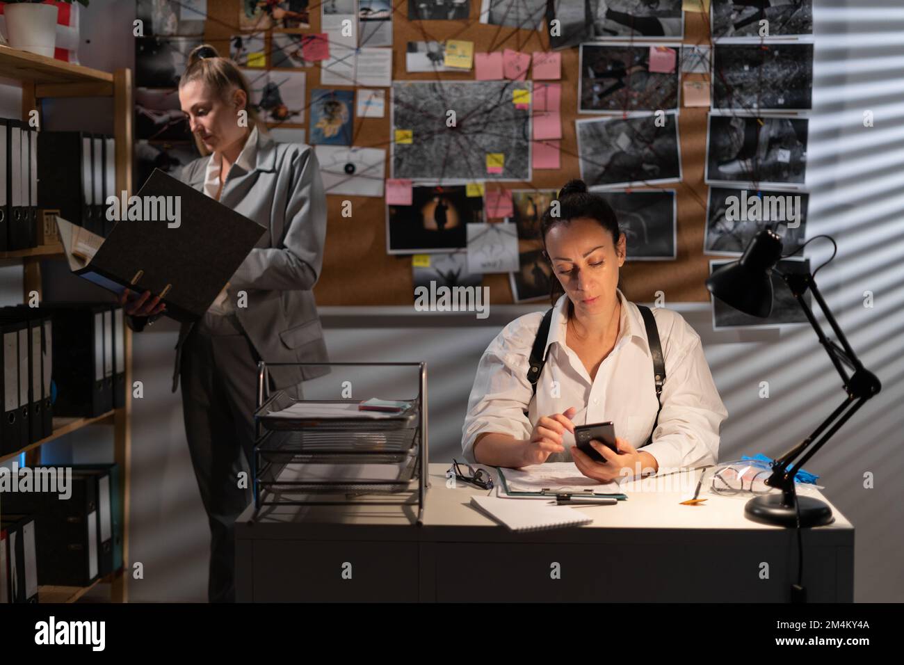 Detectives processing evidence in office using smartphone and documents ...