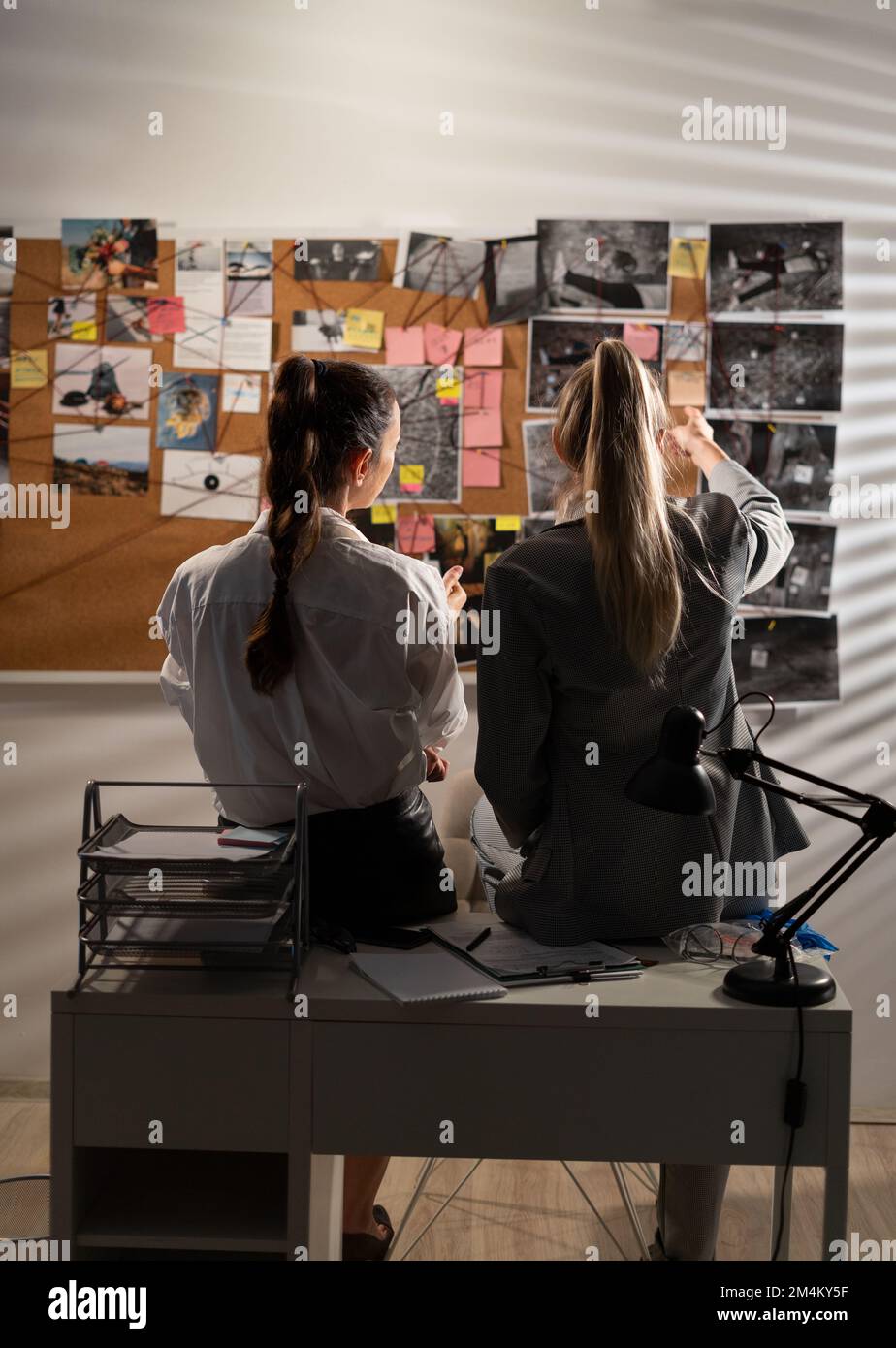 Detectives looking at evidence board in office, back view. Copy space ...