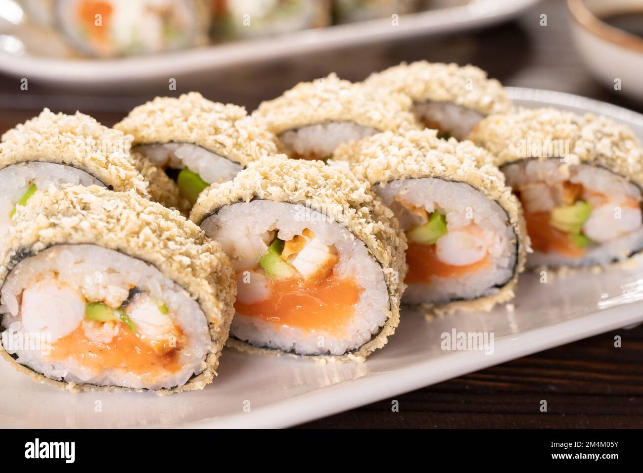 Hot tempura sushi rolls with cream cheese on white dish on black ...