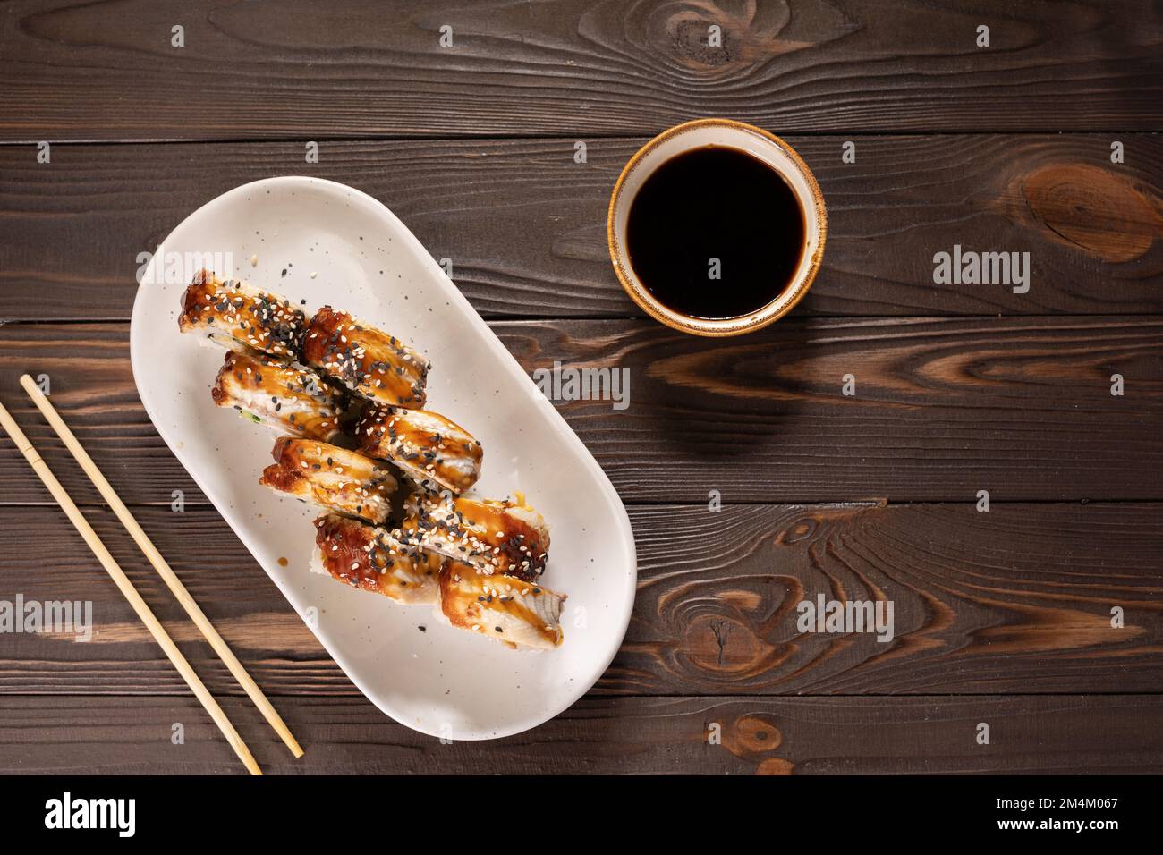 Roll sushi with eel. Canada. On wooden background on a plate, top view ...