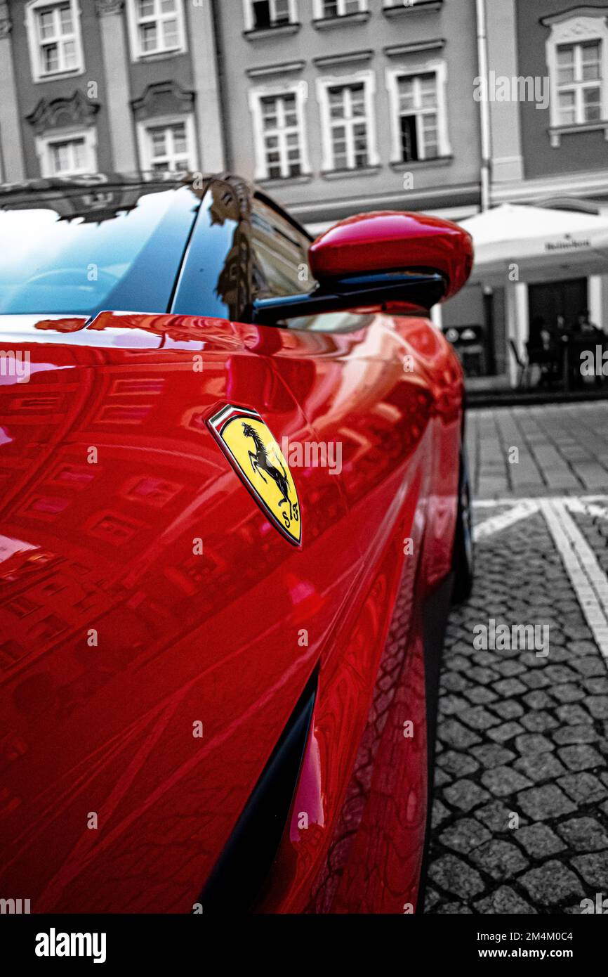 A vertical side view of a bright red Ferrari car parked on a street and ...