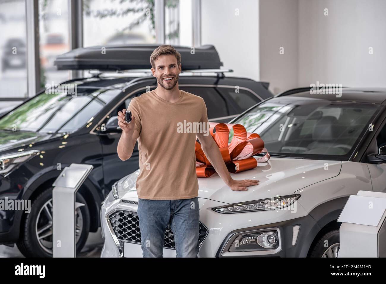 Happy young car owner standing near his new car in a car salon Stock ...