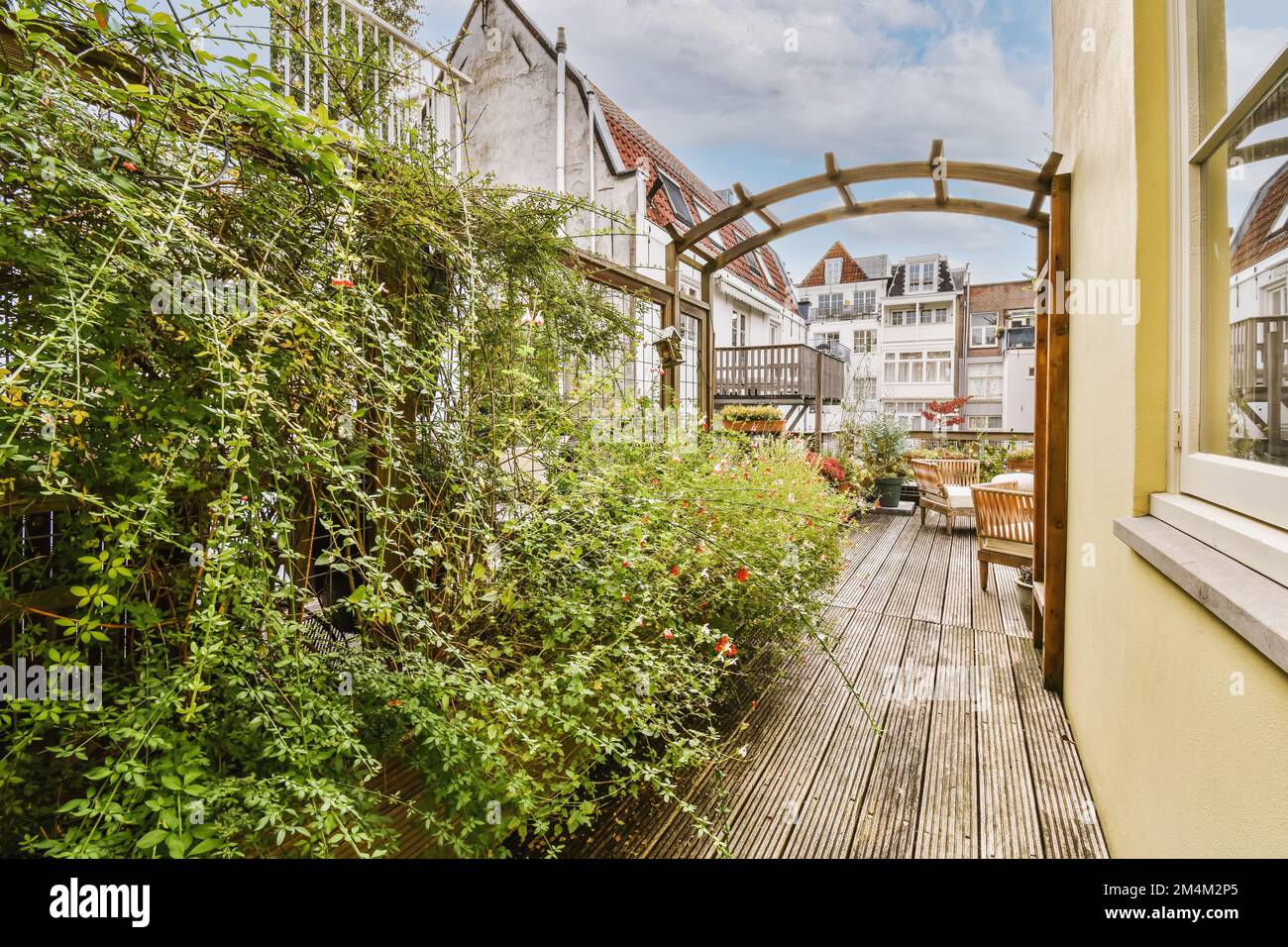 a balcony with plants growing on the wall and wooden flooring in front ...