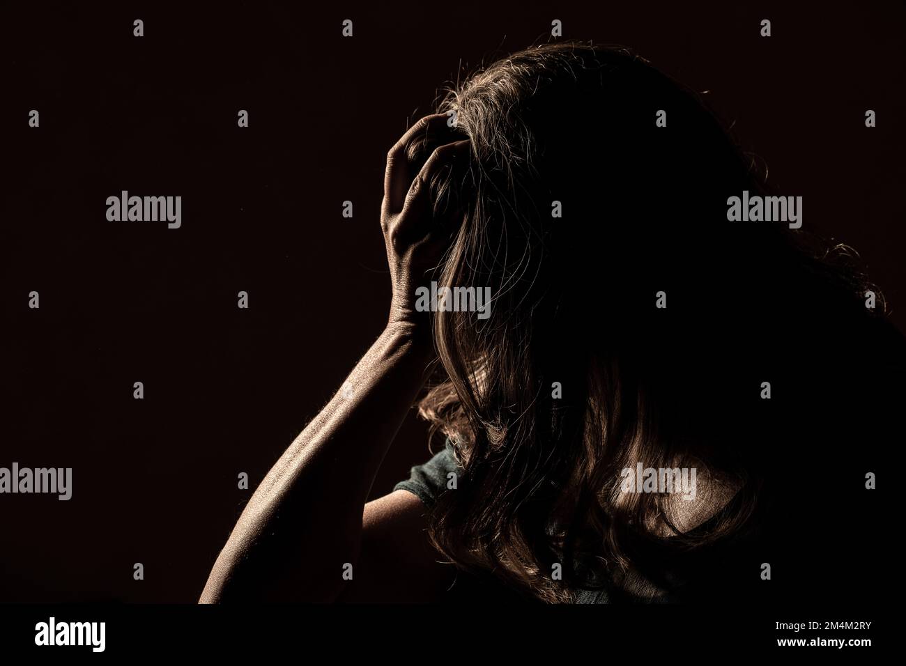 Half face of unrecognizable crying woman in shadow shrouded in darkness ...