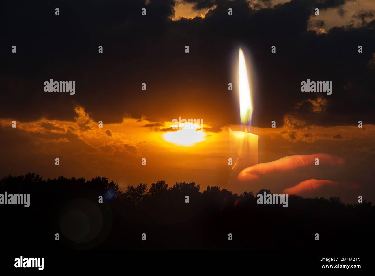 hand holds a burning candle against the background of sunset in the ...