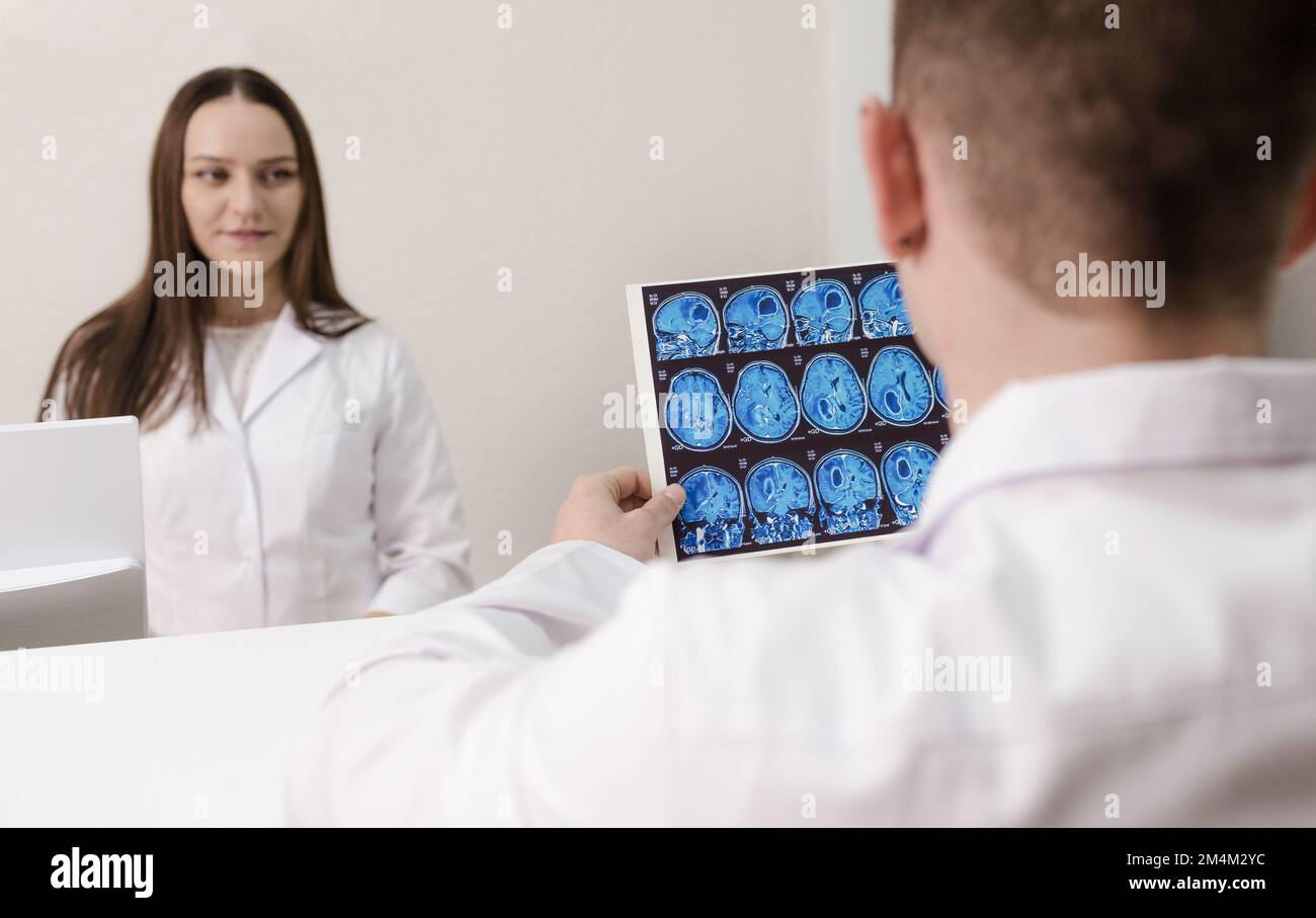 A young doctor looks at an X-ray image of a CT scan at the reception at ...