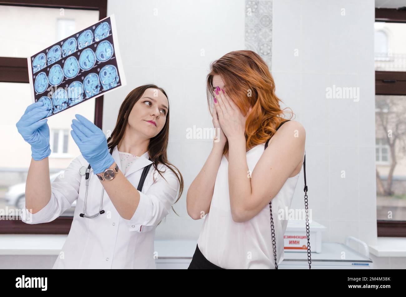 a young upset patient is crying looking at a brain tomography scan ...